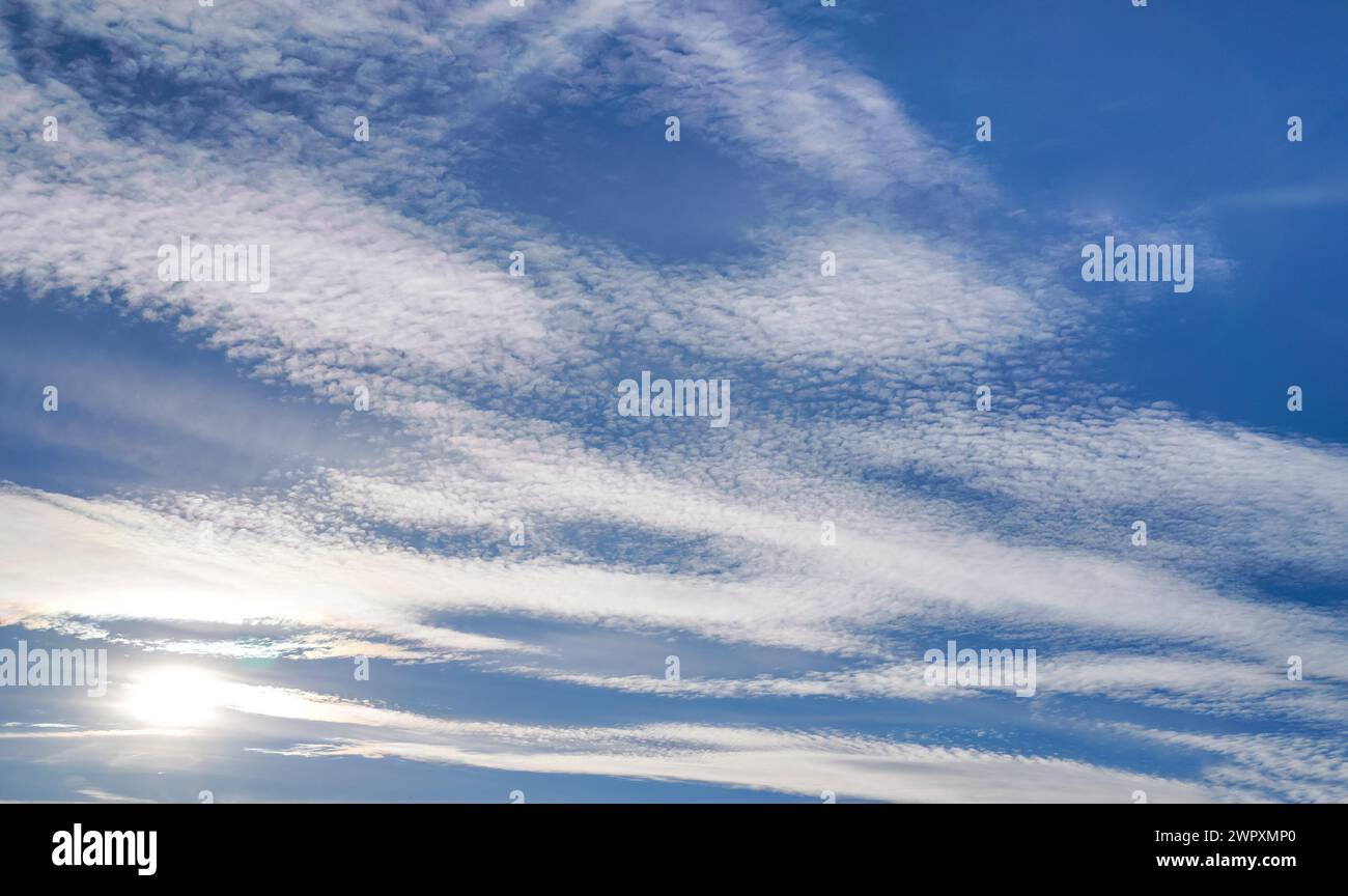 Bright sky background with few cirrus clouds, sun shines in bottom left ...