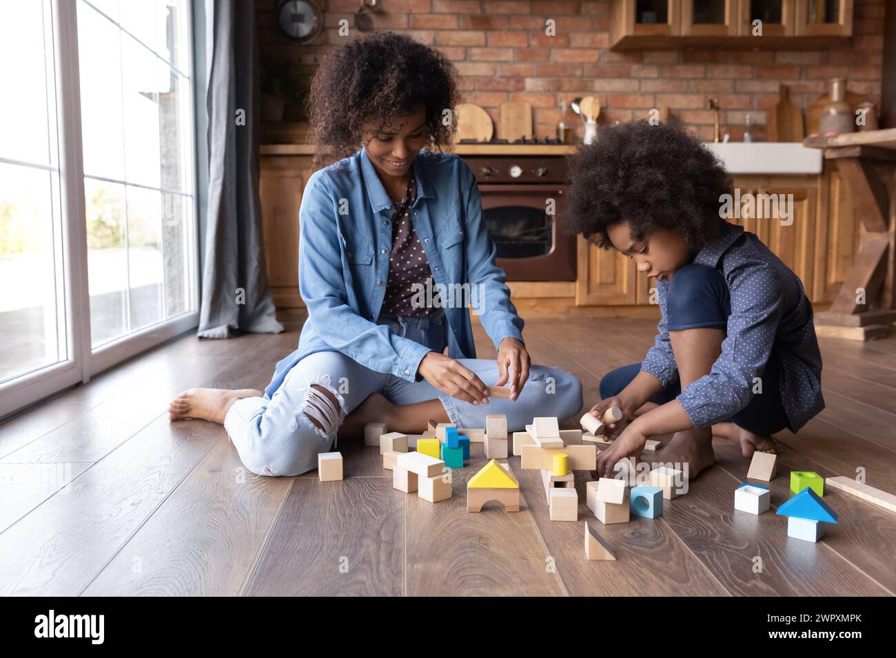African mom and daughter play wooden bricks at home Stock Photo - Alamy
