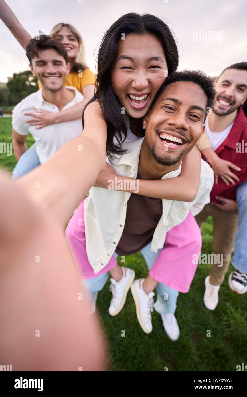 Multirracial group of friends taking selfie picture walking the park ...