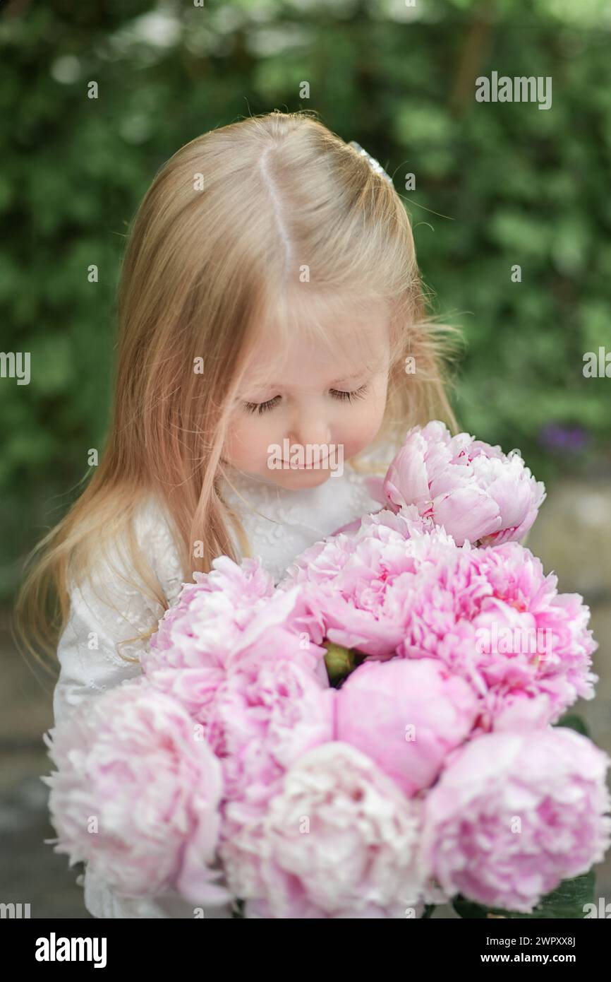 Portrait of a little girl smelling peonies Stock Photo - Alamy