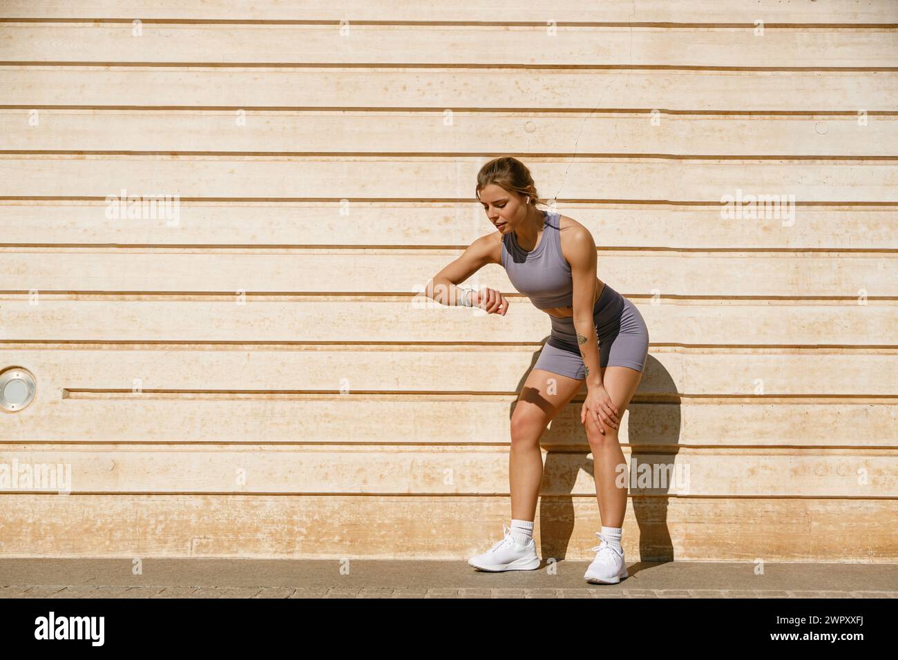 Young fit woman looking at smartwatch and counting calories burned ...