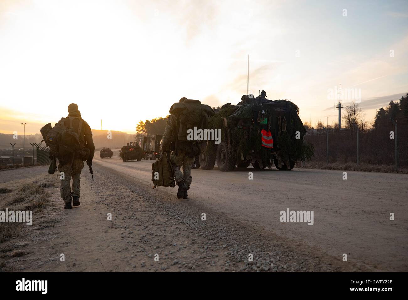 Two Lithuanian soldiers walk with their equipment towards a staging ...
