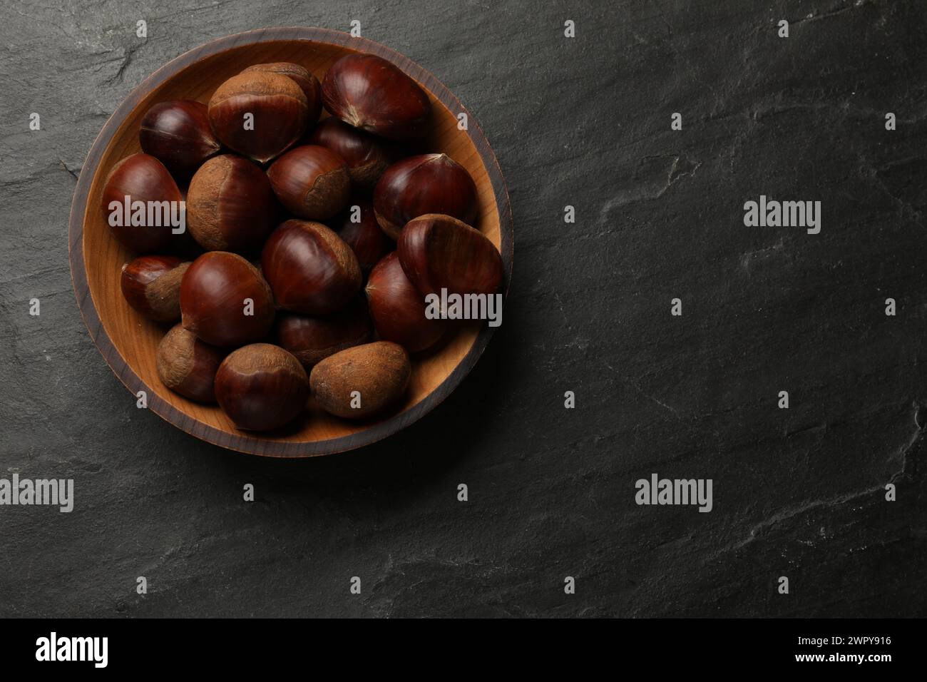 Roasted edible sweet chestnuts in bowl on grey textured table, top view ...