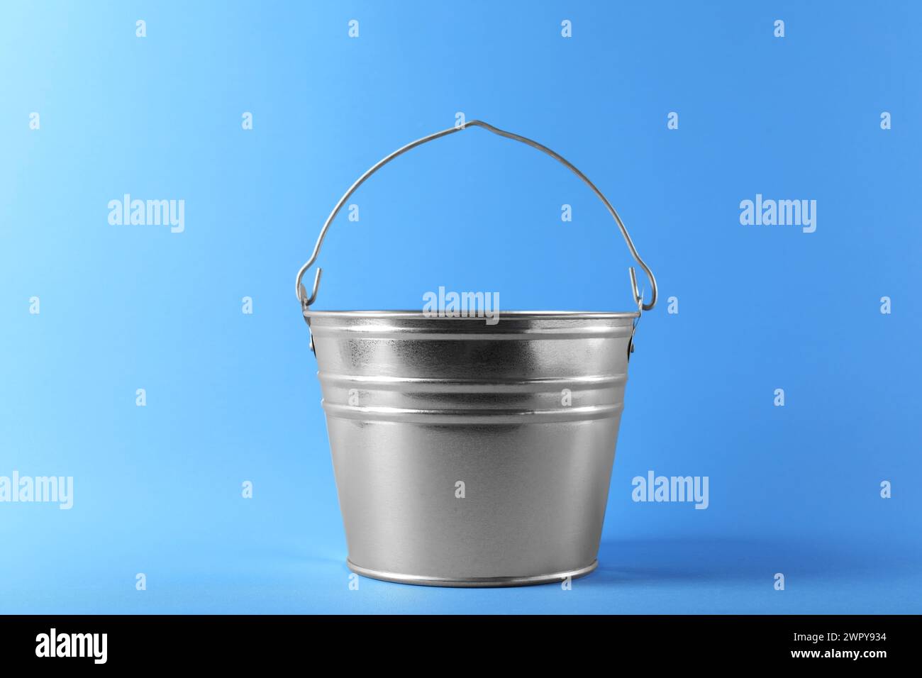 One shiny metal bucket on light blue background Stock Photo - Alamy