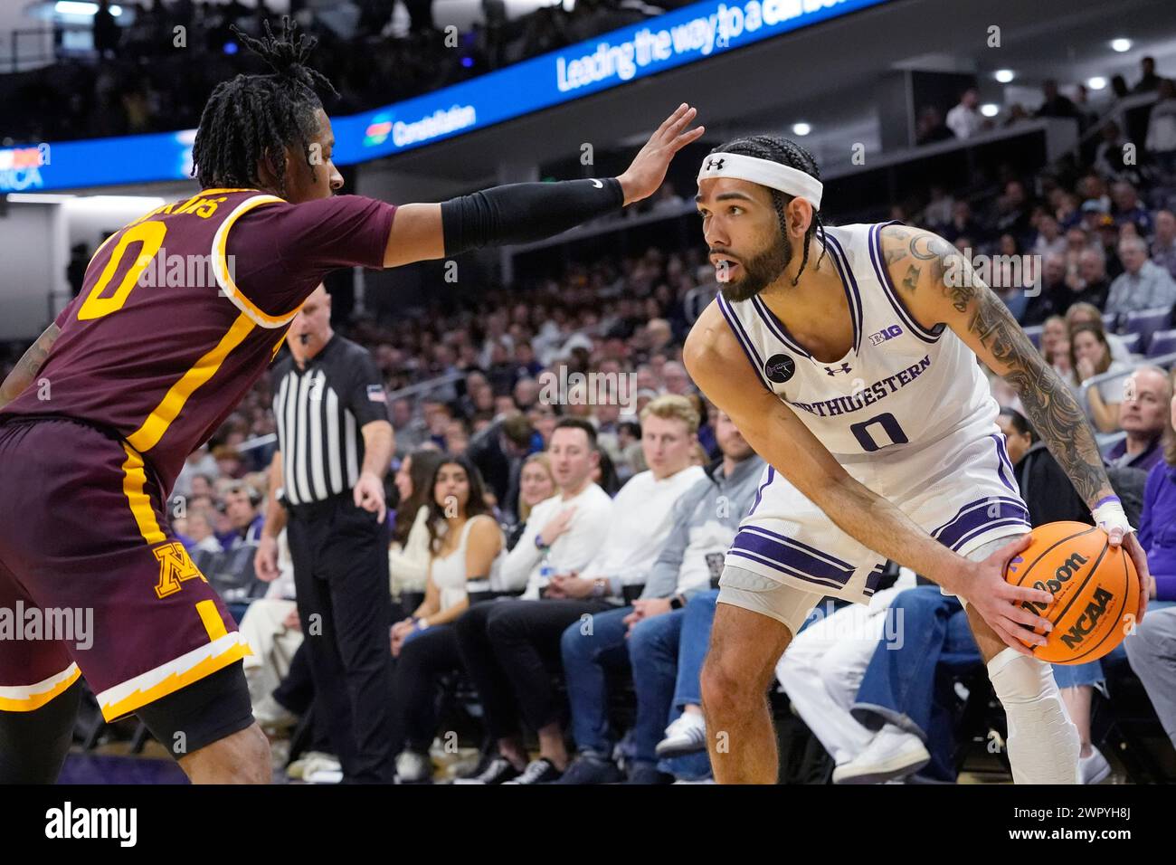 Northwestern guard Boo Buie, right, looks to pass the ball as Minnesota ...