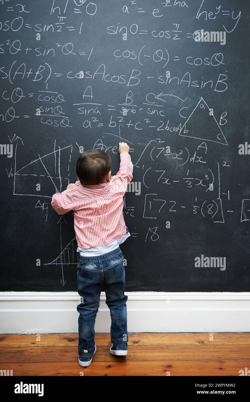 Child, math and blackboard with writing in classroom for knowledge ...