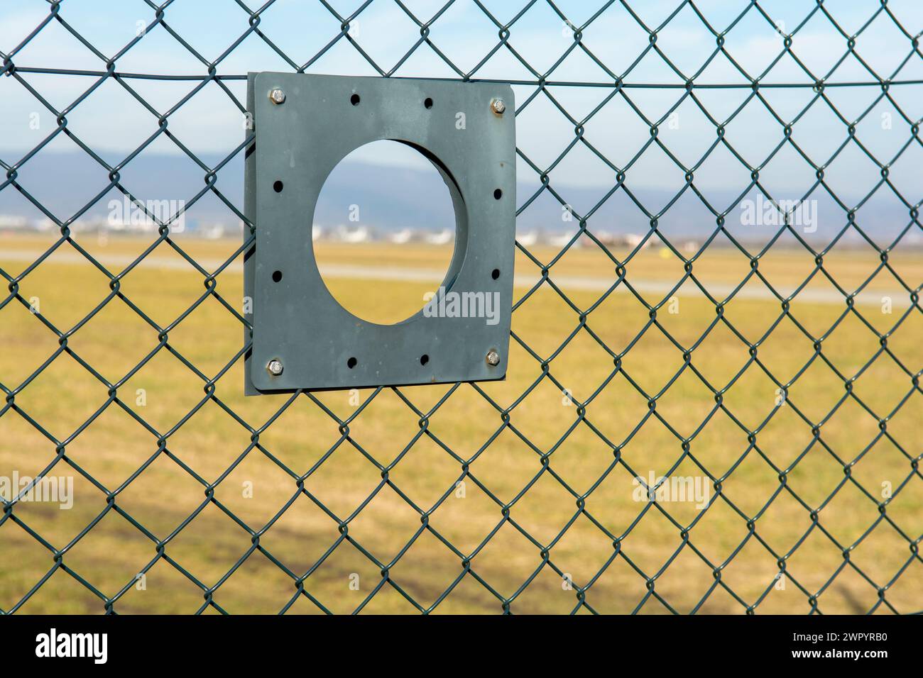 Small opening in the green steel wire mesh fence around the airport ...