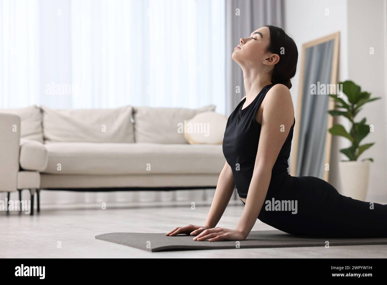 Girl practicing cobra asana on yoga mat at home. Bhujangasana pose ...