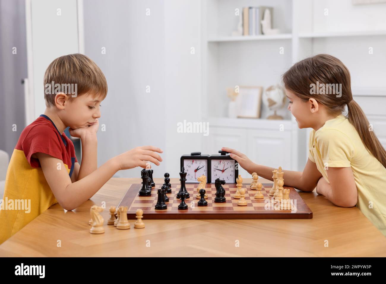 Cute children playing chess at table in room Stock Photo - Alamy