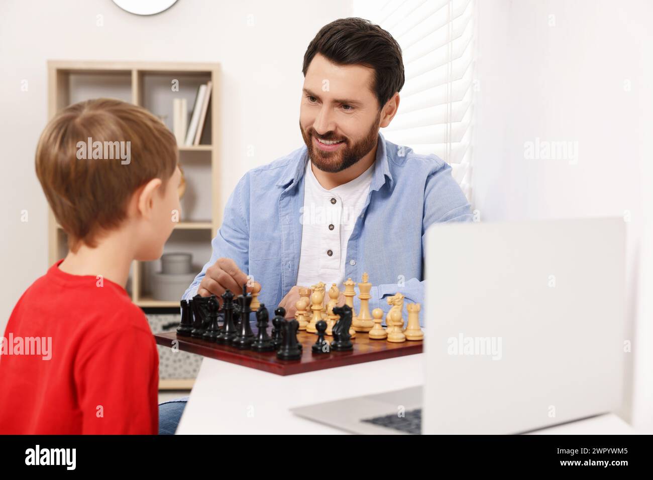 Father and son playing chess following online lesson in room Stock ...