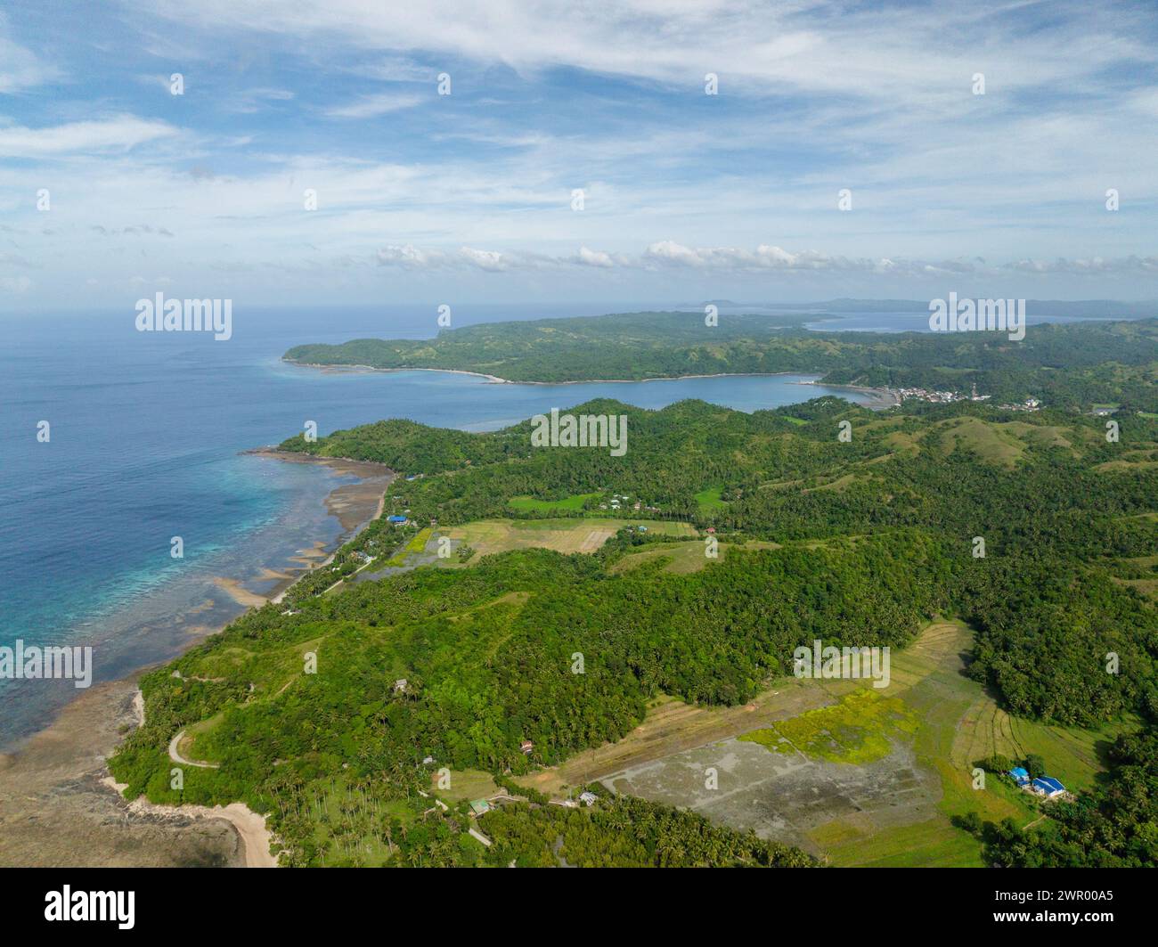 Tropical Island with green hills and farmlands. Turquoise water at ...