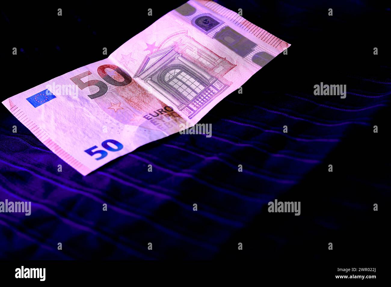 Money. 50 euro banknote being examined under ultraviolet light on a ...