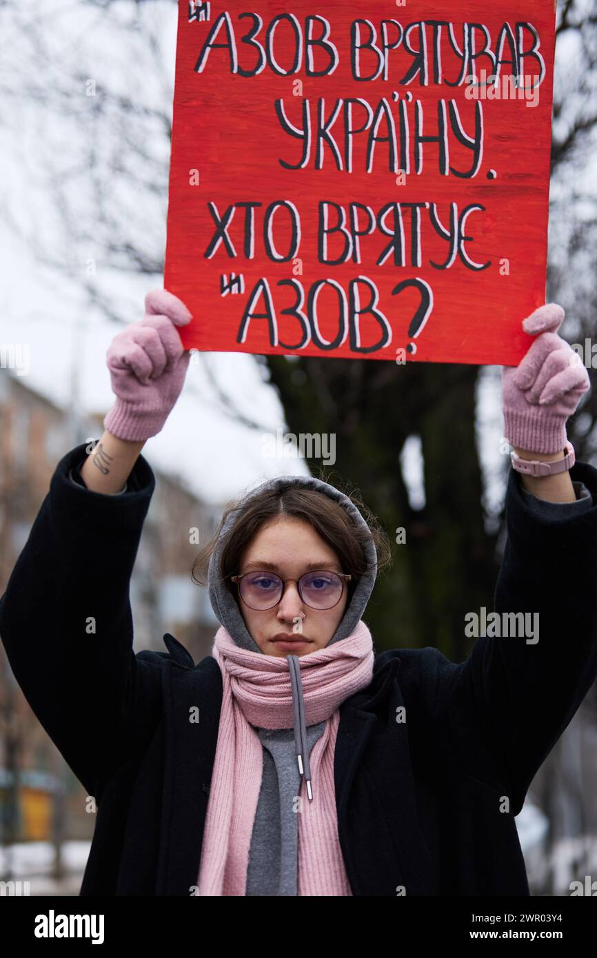 Ukrainian activist posing with a banner "Azov Saved Ukraine. Who Will ...