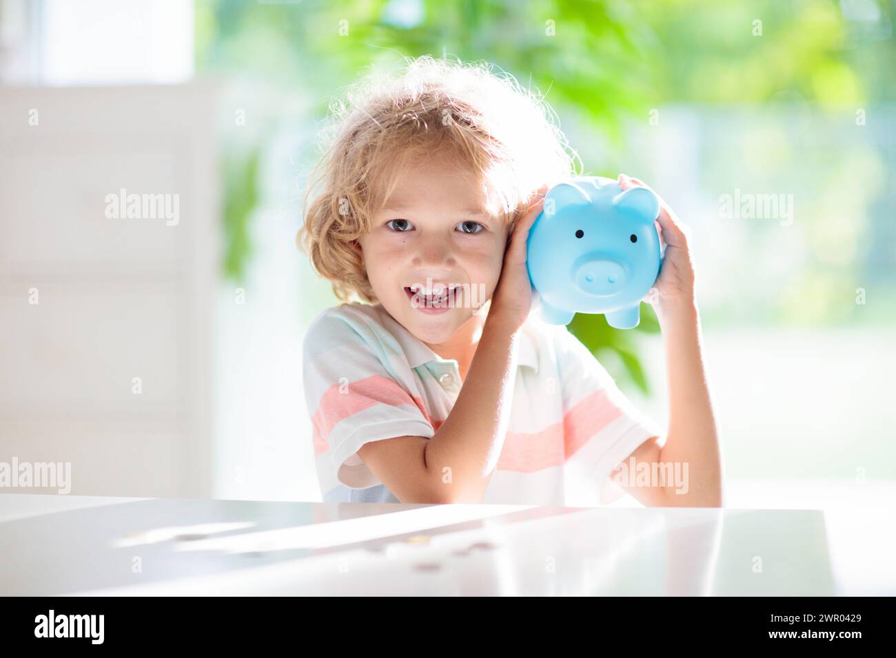 Child putting coin in piggy bank. Kids learn about money. Savings and ...
