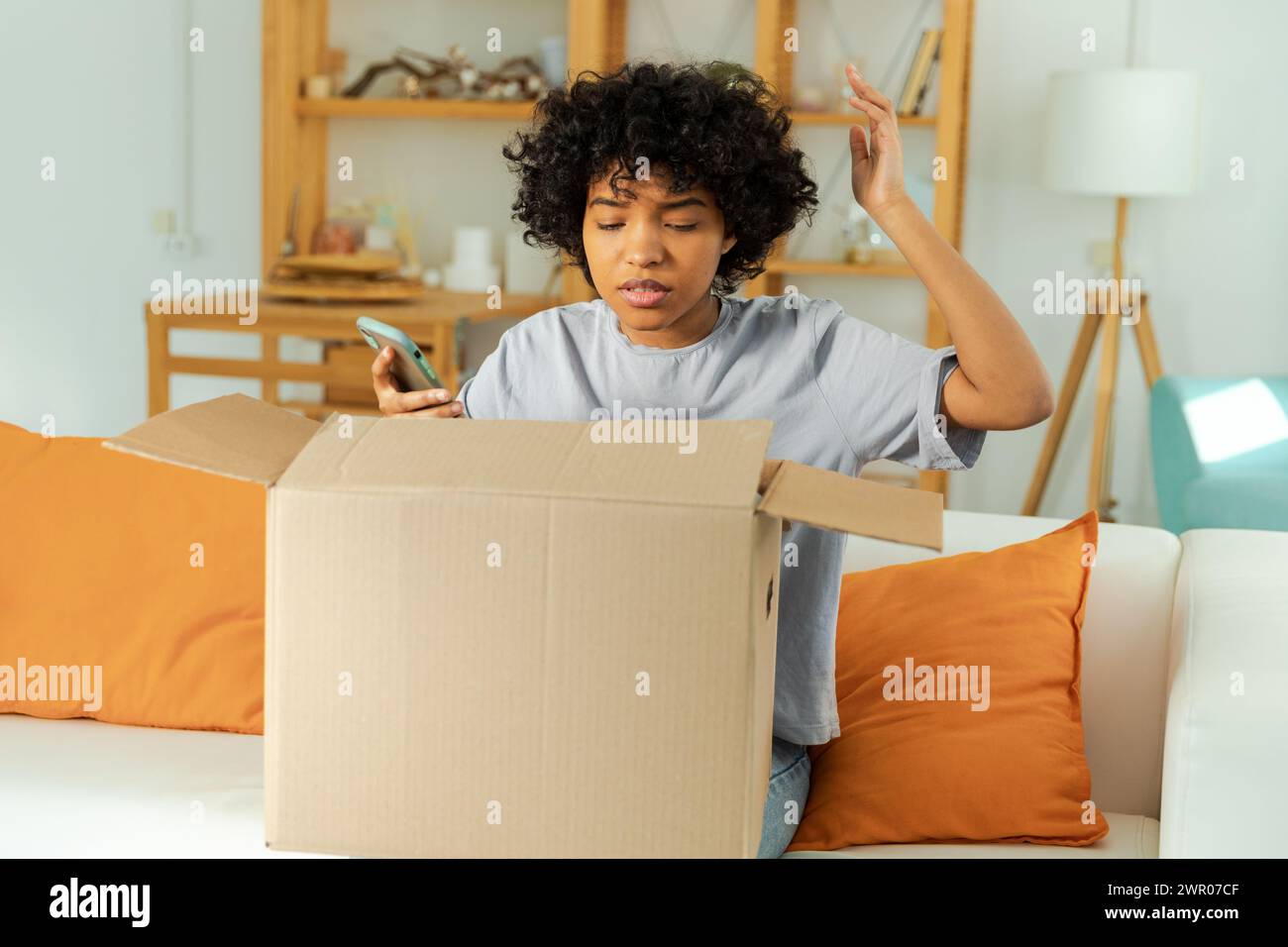 Unhappy african woman unpack delivered box receiving damaged shipping ...