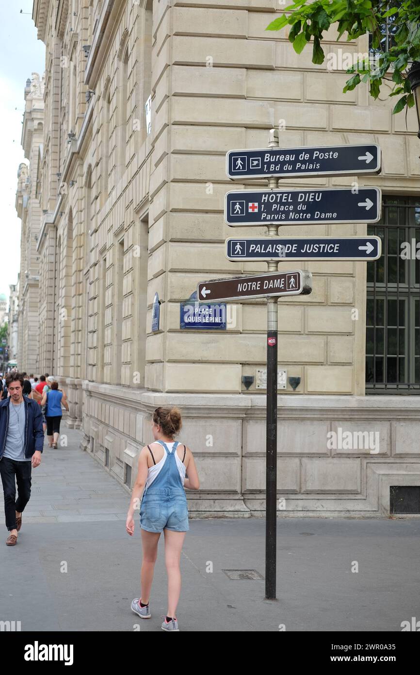 A woman waking past place tourist direction signs at place Louis-Lépine ...
