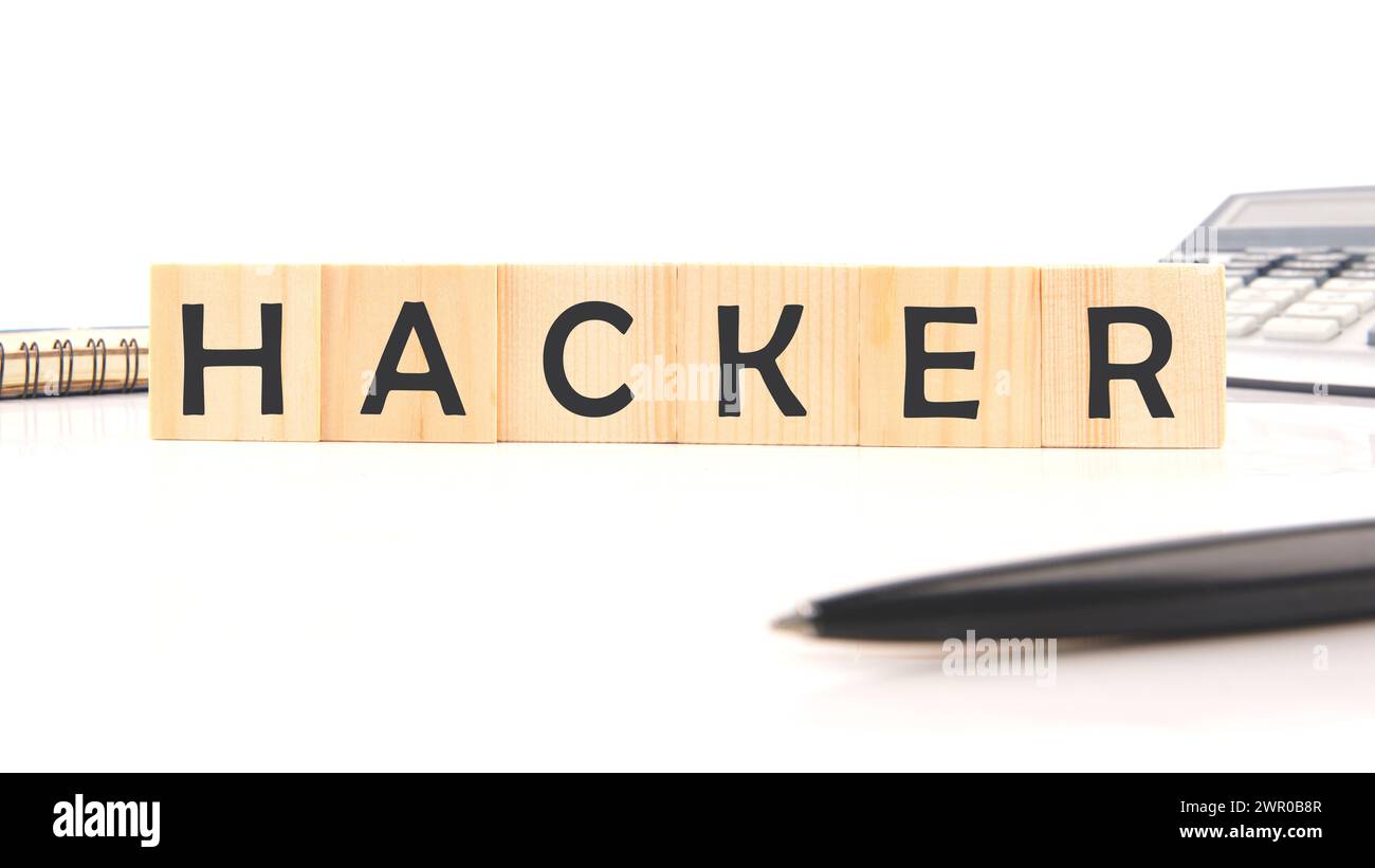 Hacker word on wooden cubes next to a calculator, pen, notepad on a ...