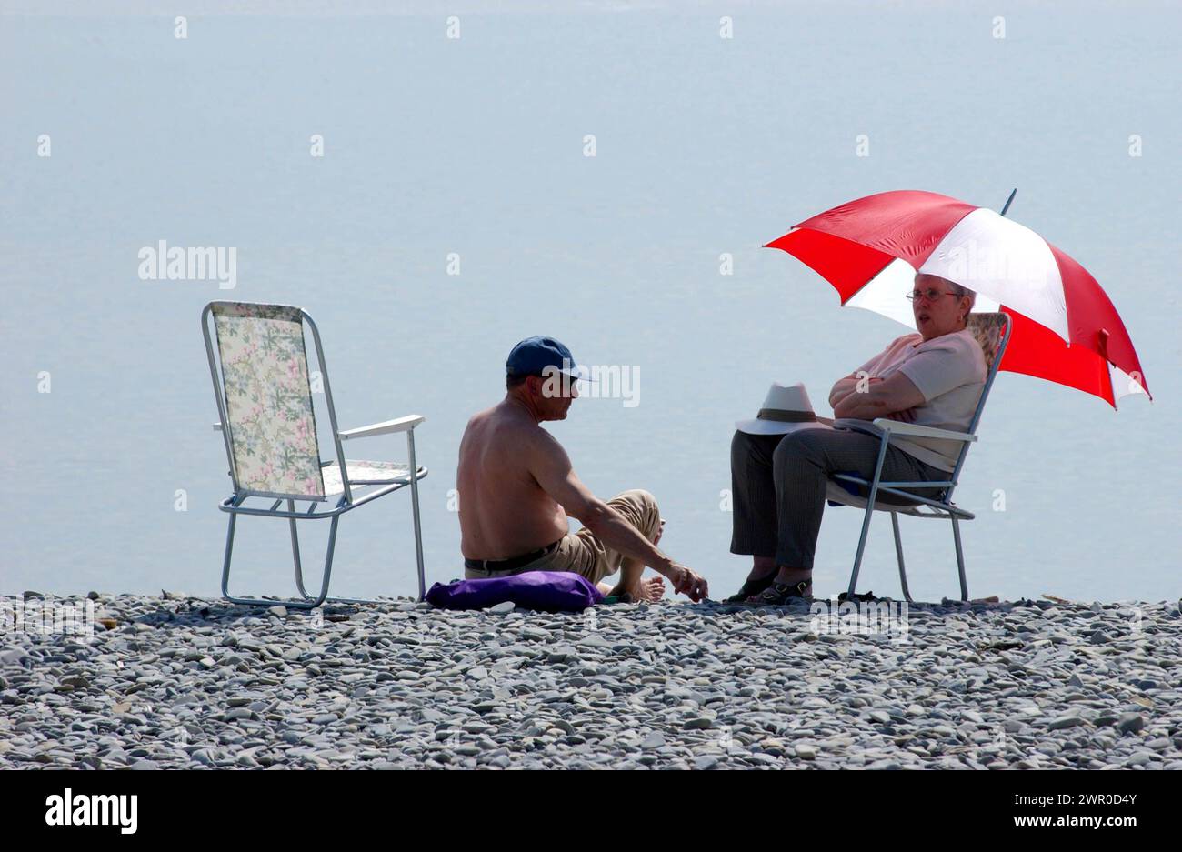 A couple sunbathing on the sloping pebble beach at Cold Knapp near ...