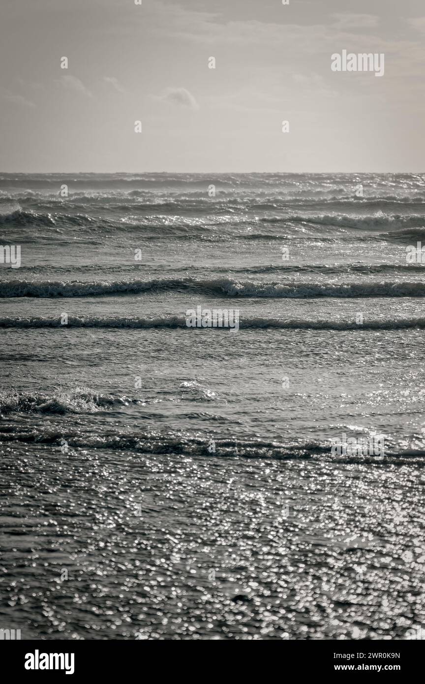 Low colour seascape in vertical format; shallow waves in the foreground ...