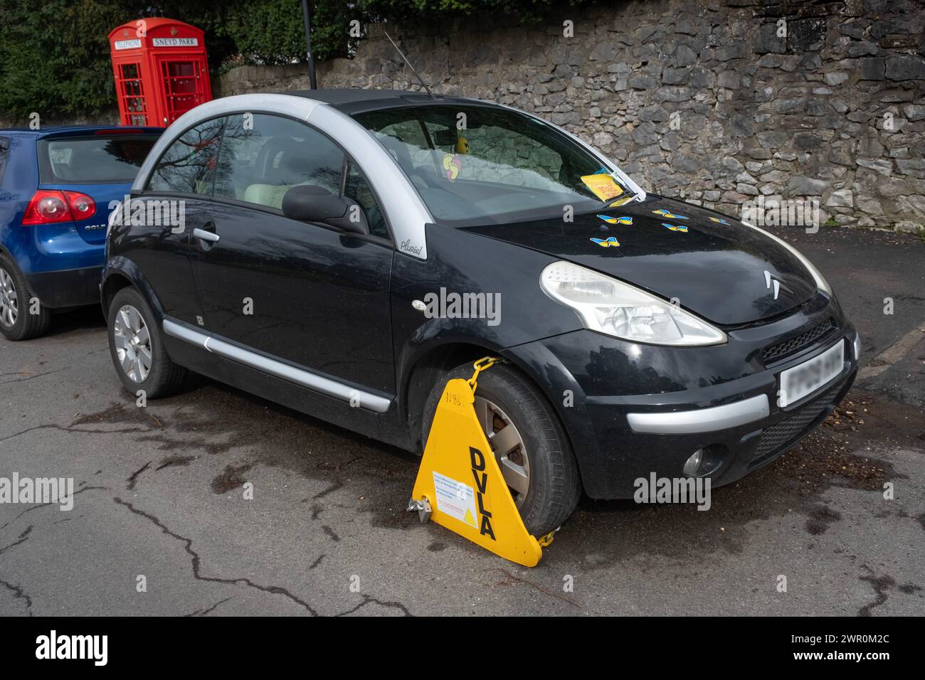 Untaxed car with a wheel clamp on a street Stock Photo - Alamy
