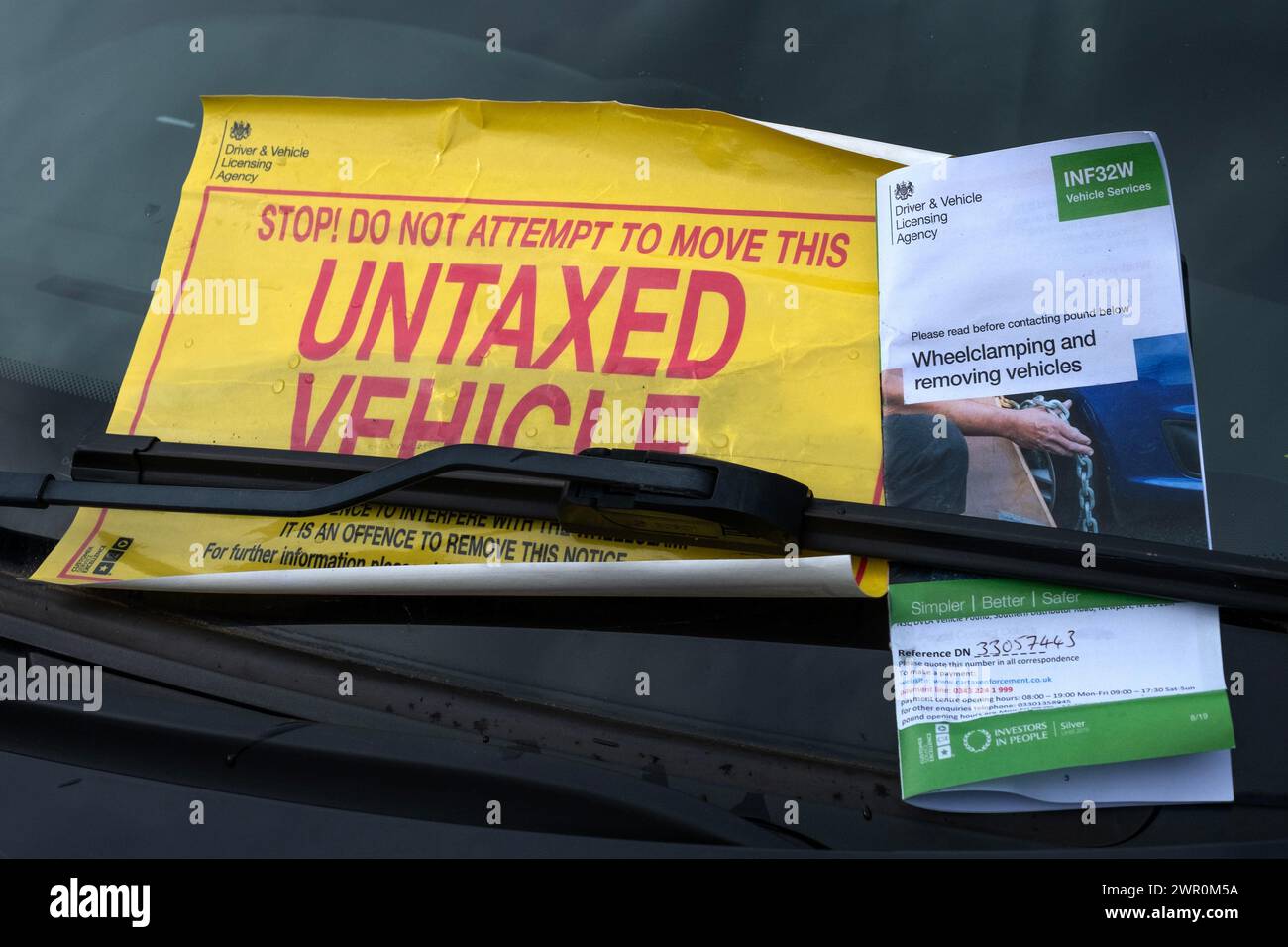 Untaxed car with a wheel clamp on a street Stock Photo - Alamy