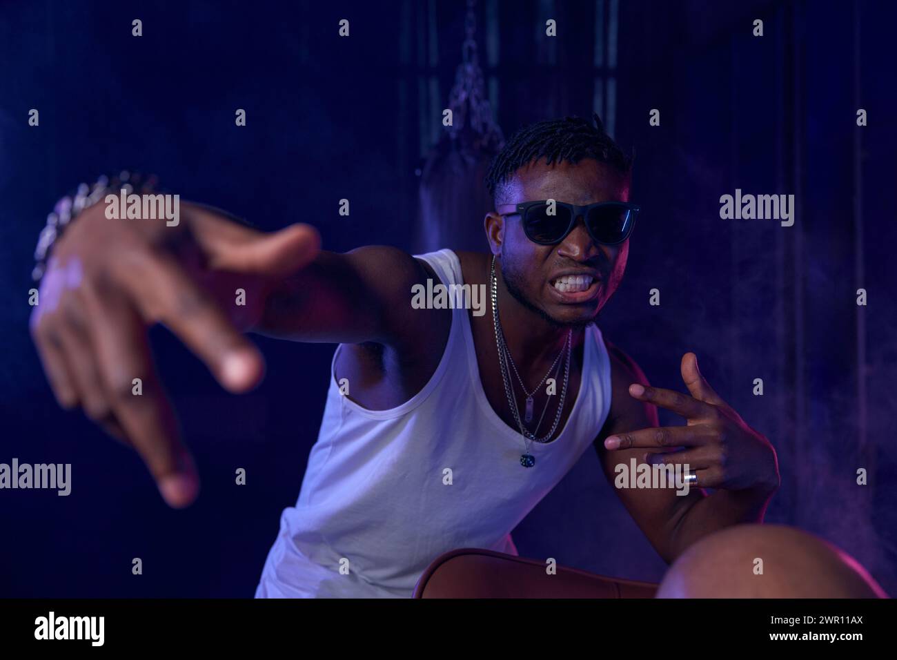 Young guy rapper posing for camera in neon light Stock Photo - Alamy