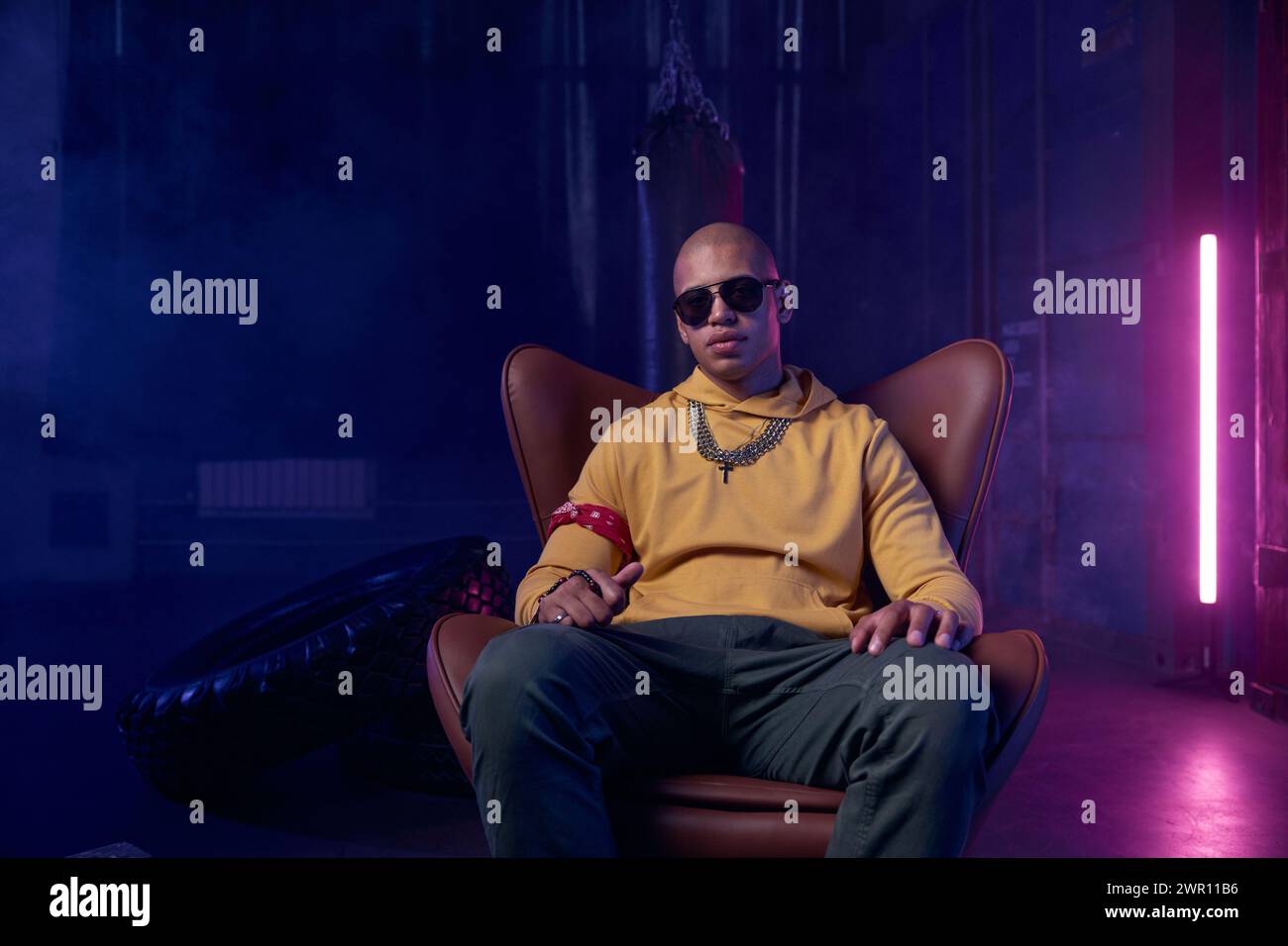Young serious gang leader sitting in leather armchair in garage Stock ...