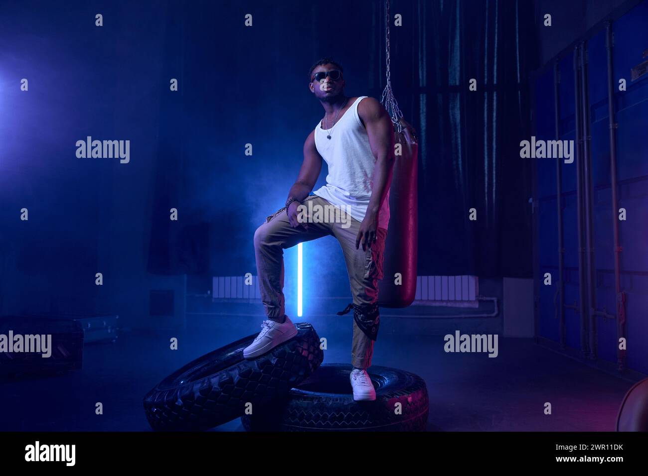 Trendy fashion muscular rapper standing in neon lights of cool ...