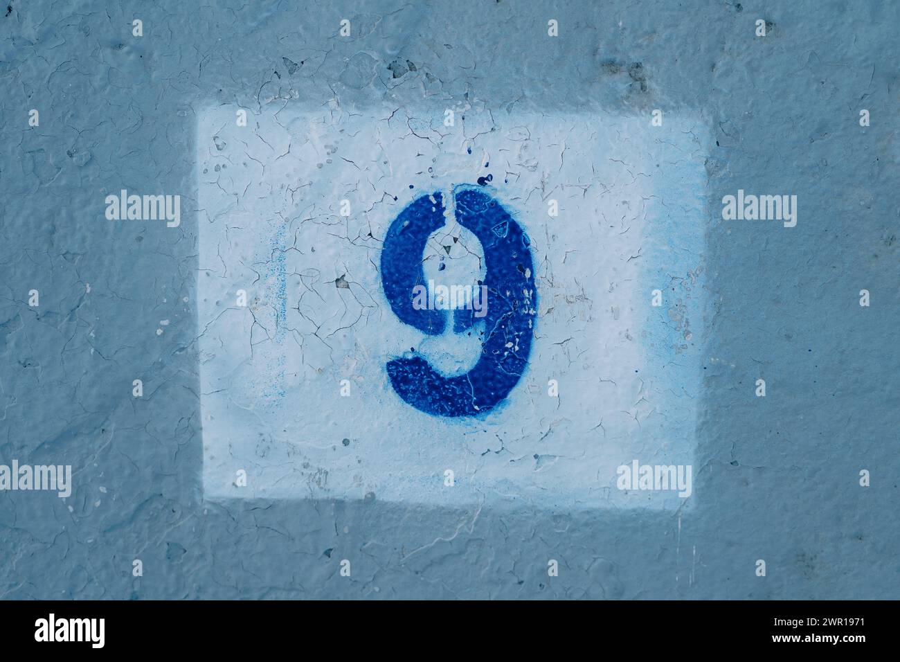 Number nine drawn on a scratched blue wall in a white rectangle Stock ...