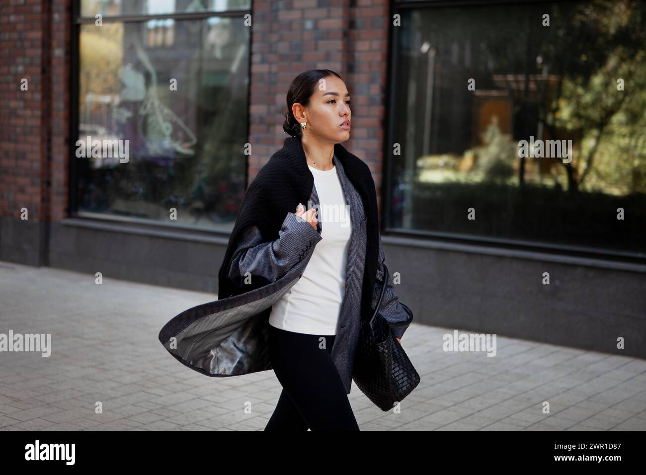 Stylish fashion woman strolls down the street in multilayer clothes ...