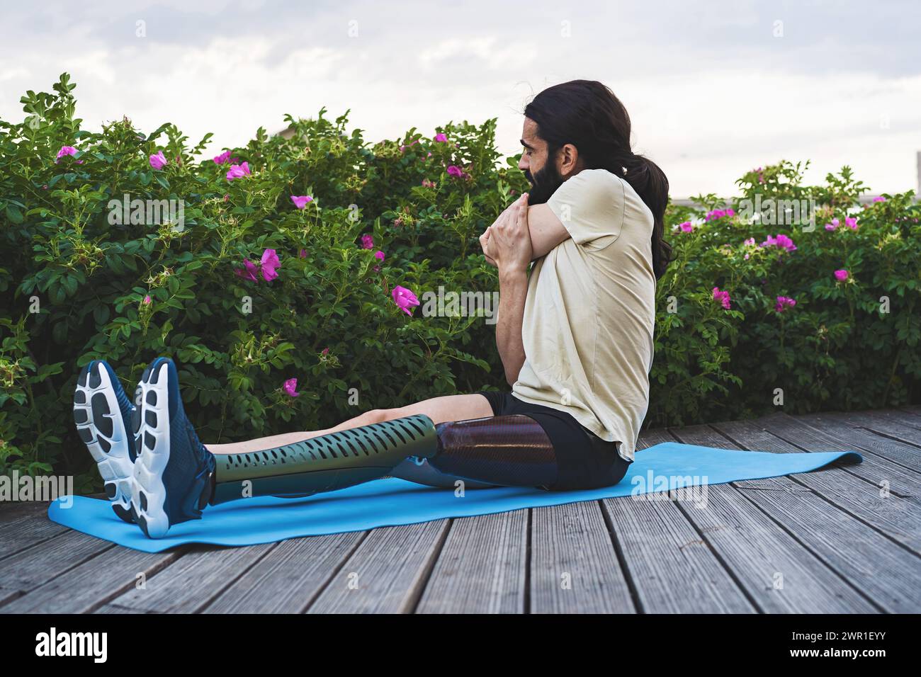 Amputee using a leg prosthesis performing a stretching exercise ...