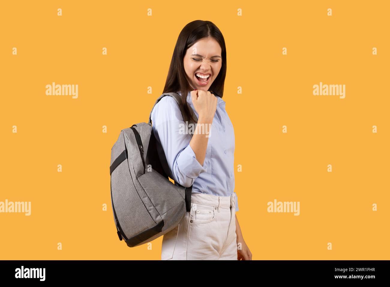 Joyful female student celebrating with fist pump, feeling victorious ...