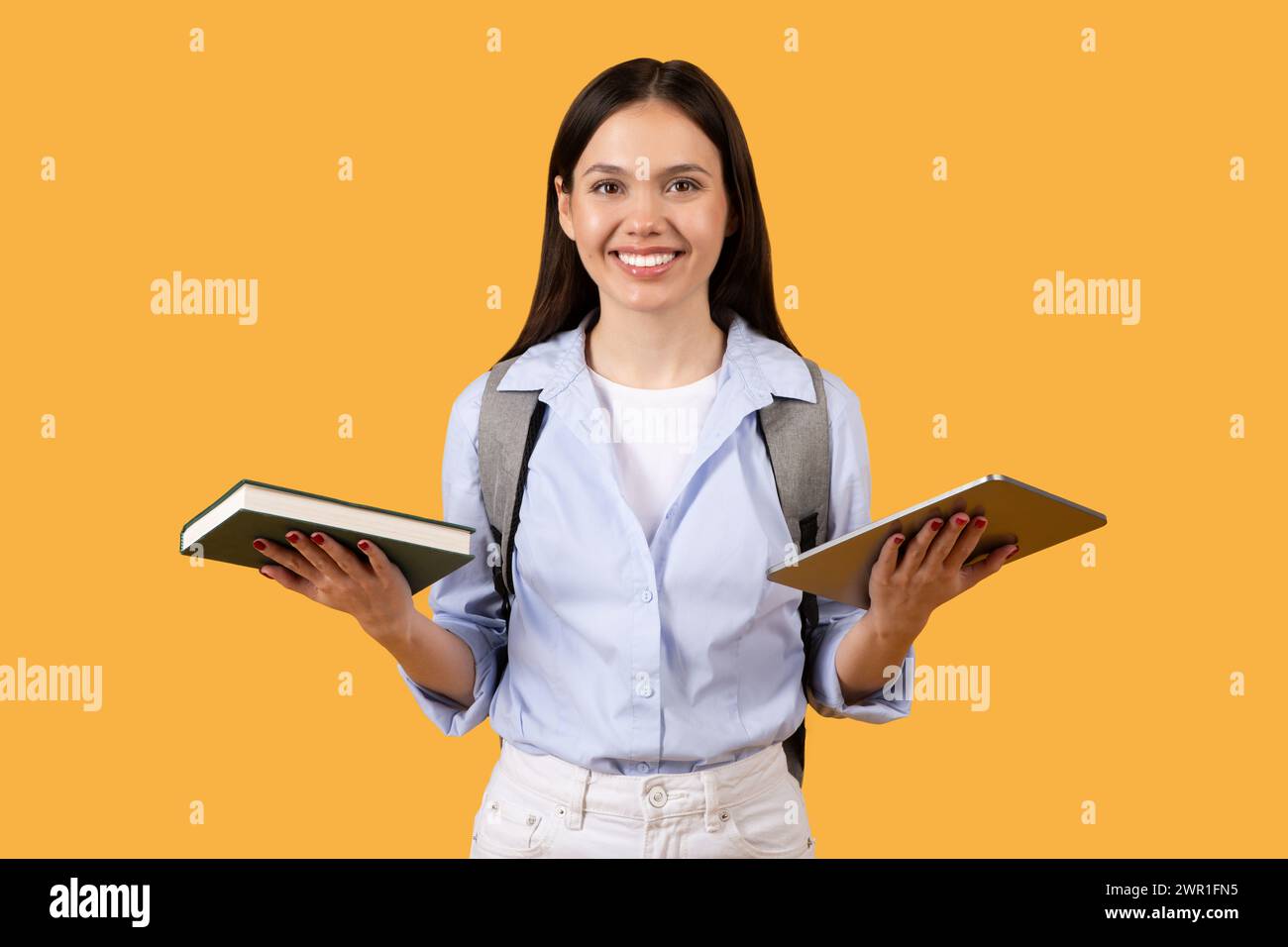 Student lady comparing book and tablet against yellow backdrop Stock ...