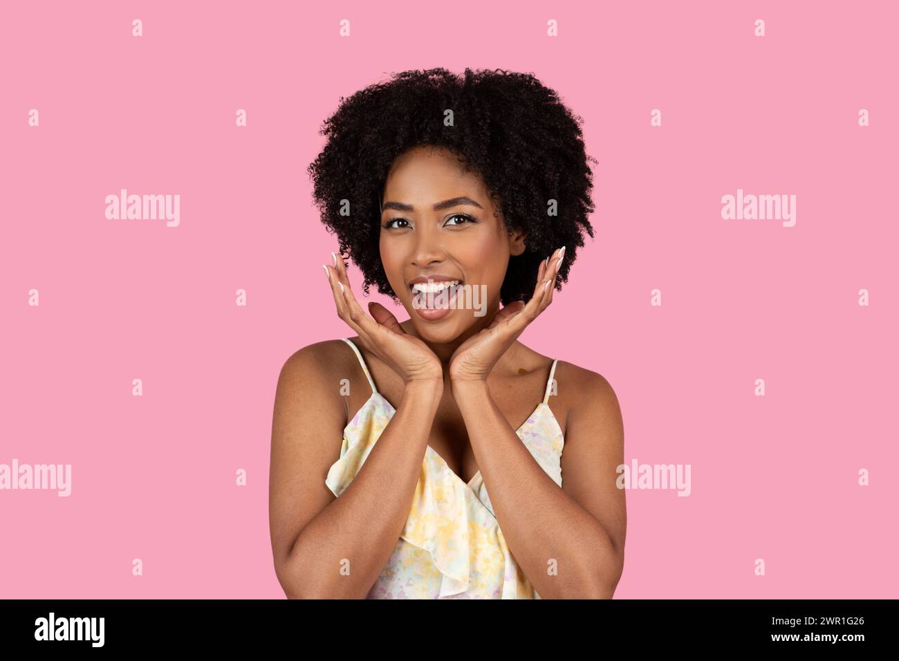 An exuberant young African American woman with curly afro hair joyfully ...