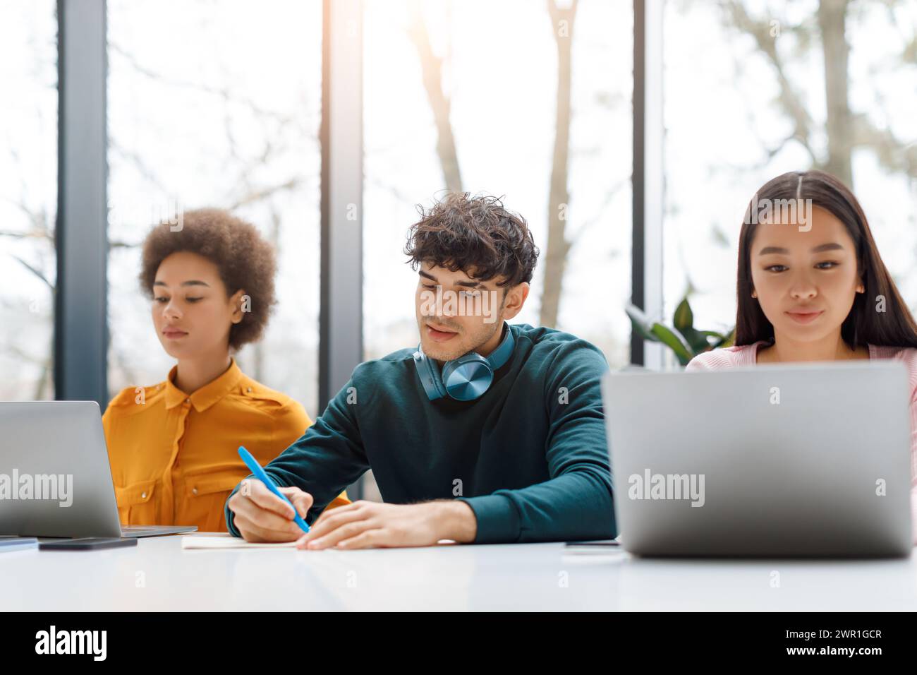 Diverse students focused on their tasks with laptops and notes Stock ...