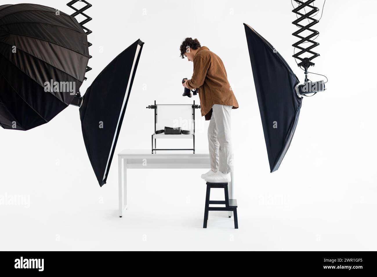 Photographer on stool in studio with lighting setup Stock Photo - Alamy