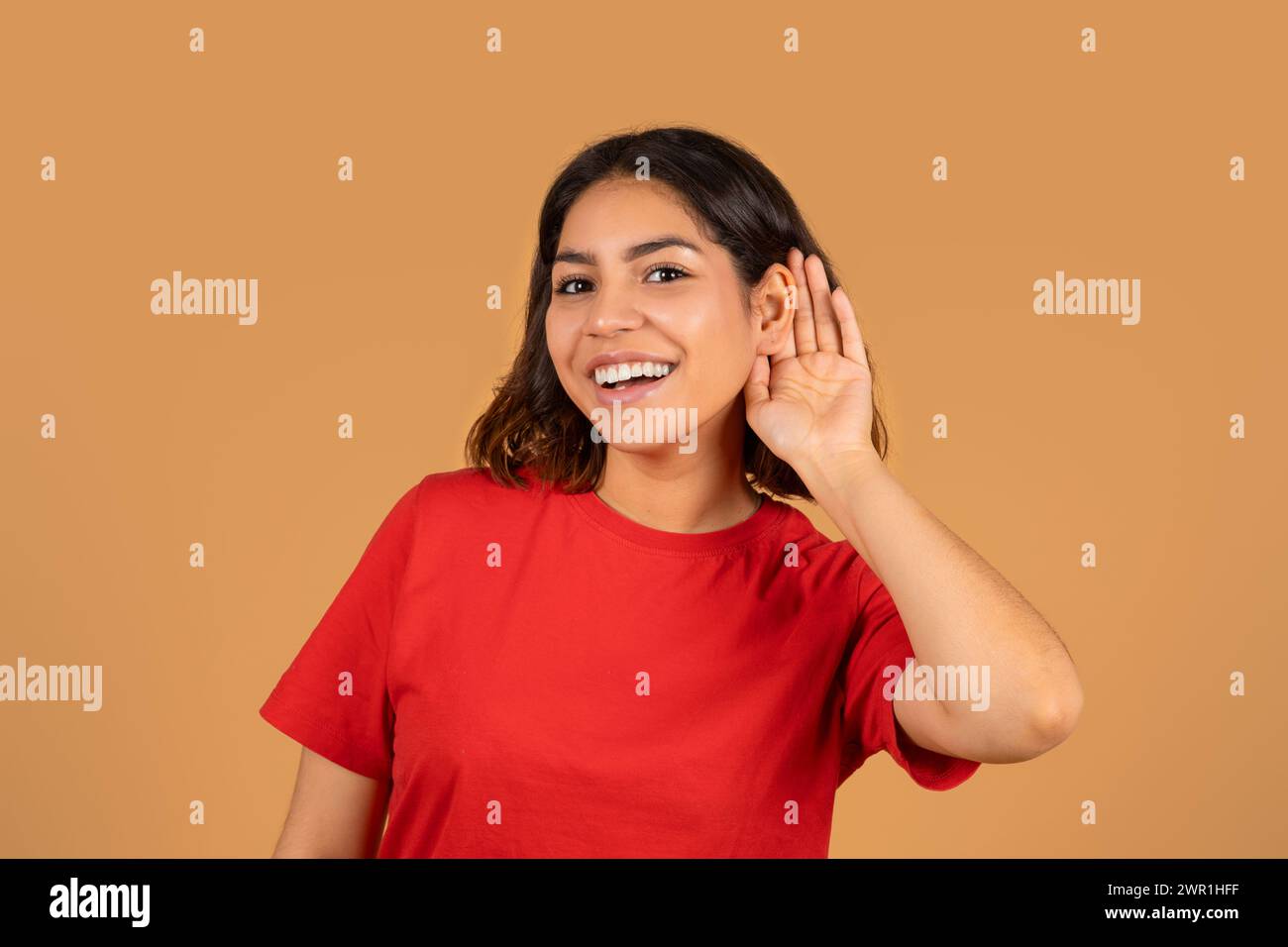 Curious excited young arabic woman touching her ear with hand Stock ...
