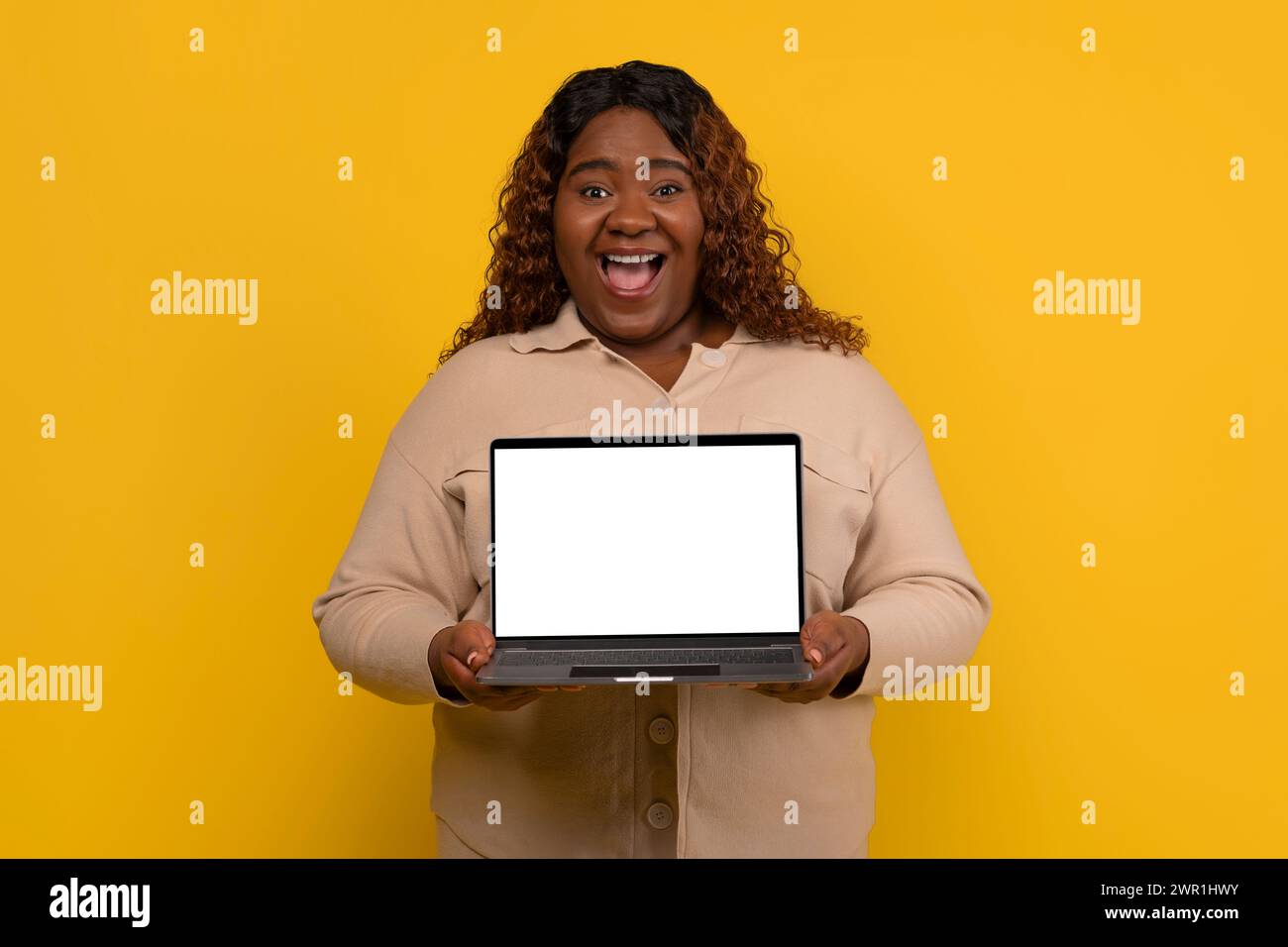 Emotional plump black lady showing laptop with blank screen Stock Photo ...