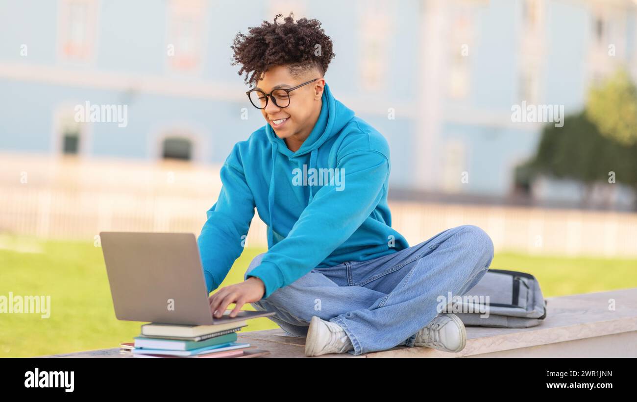 black student guy typing and browsing web on laptop outdoor Stock Photo ...