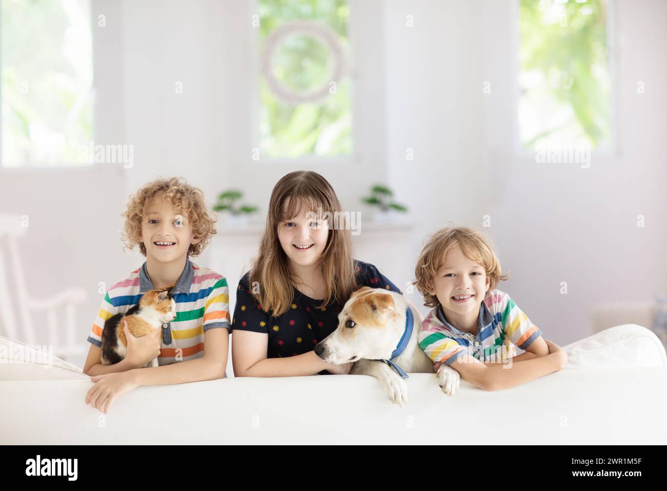 Kids play and watch tv on white couch. Children at home. Sunny family ...