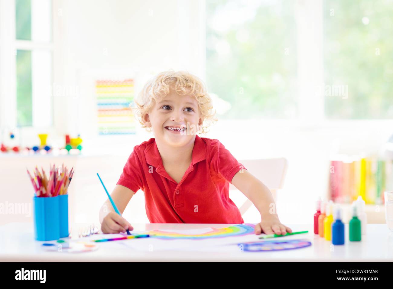 Kids paint. Child painting in white sunny study room. Little boy ...
