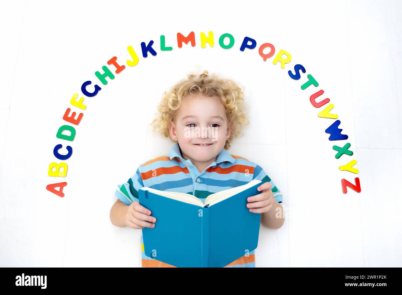 Happy preschool child learning to read and write playing with colorful ...