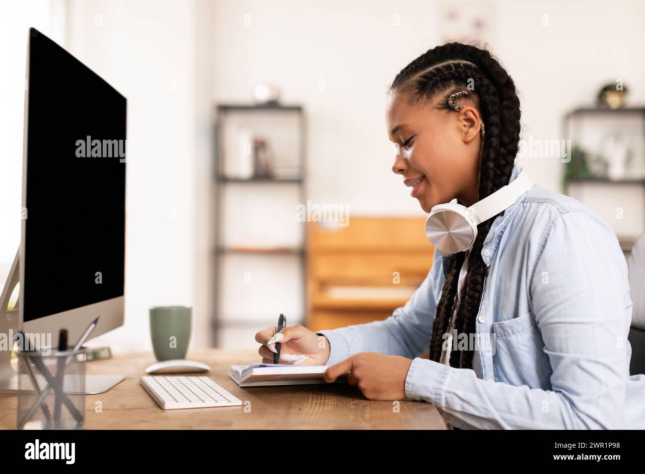 Focused lady student with headphones taking notes from computer Stock ...