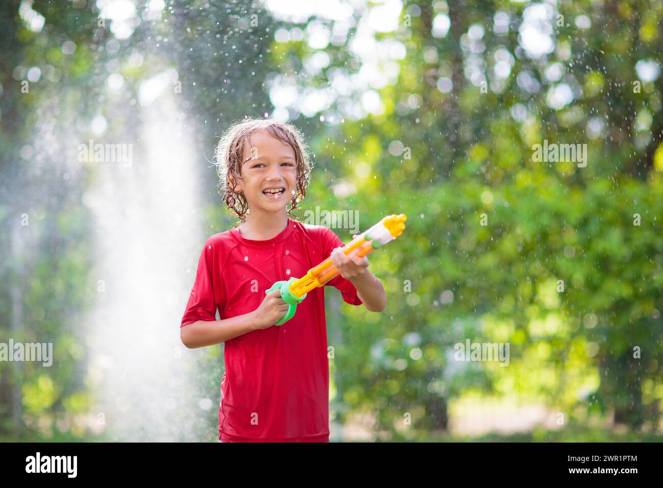 Kids play with water sprinkle hose. Summer garden outdoor fun for ...
