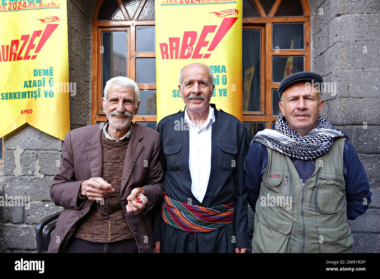 Three Kurds in traditional clothes are seen in front of the Newroz 2024 ...