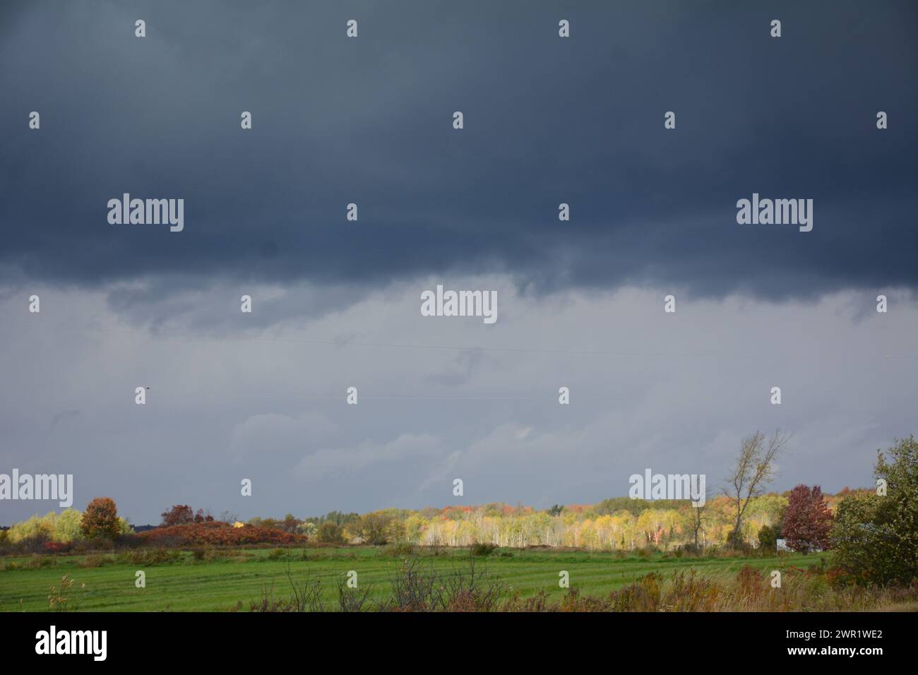 Distant white farmhouse reflected in water on driveway before storm ...