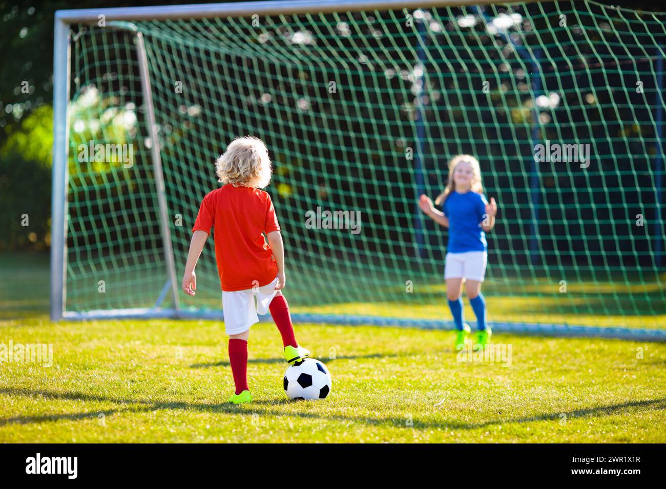 Kids play football on outdoor field. Children score a goal at soccer ...