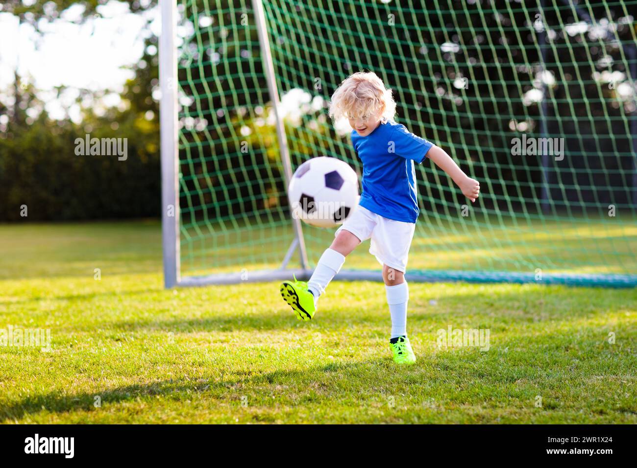 Kids play football on outdoor field. Children score a goal during ...