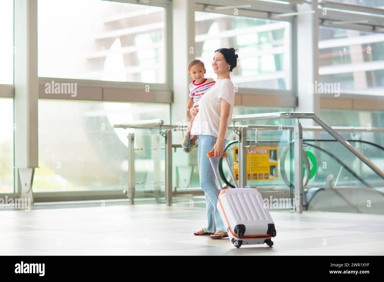Family in airport. Young Asian mother and child travel by air. Fly with ...