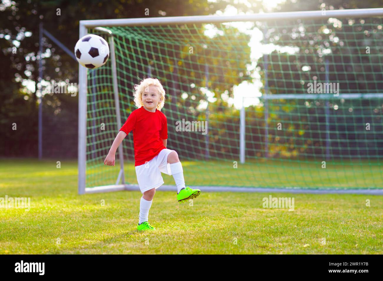 Kids play football on outdoor field. Children score a goal during ...